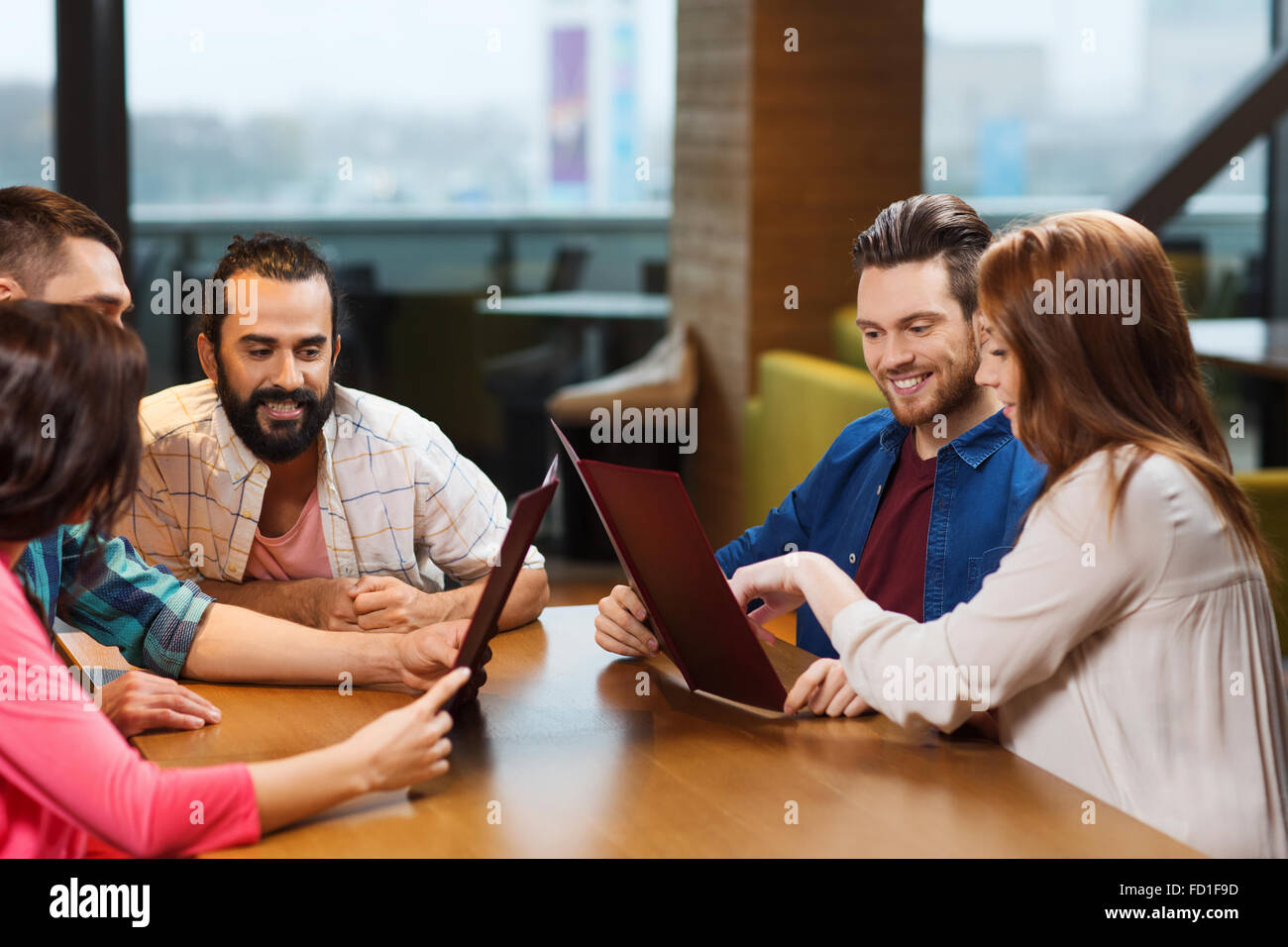 smiling friends discussing menu at restaurant Stock Photo - Alamy