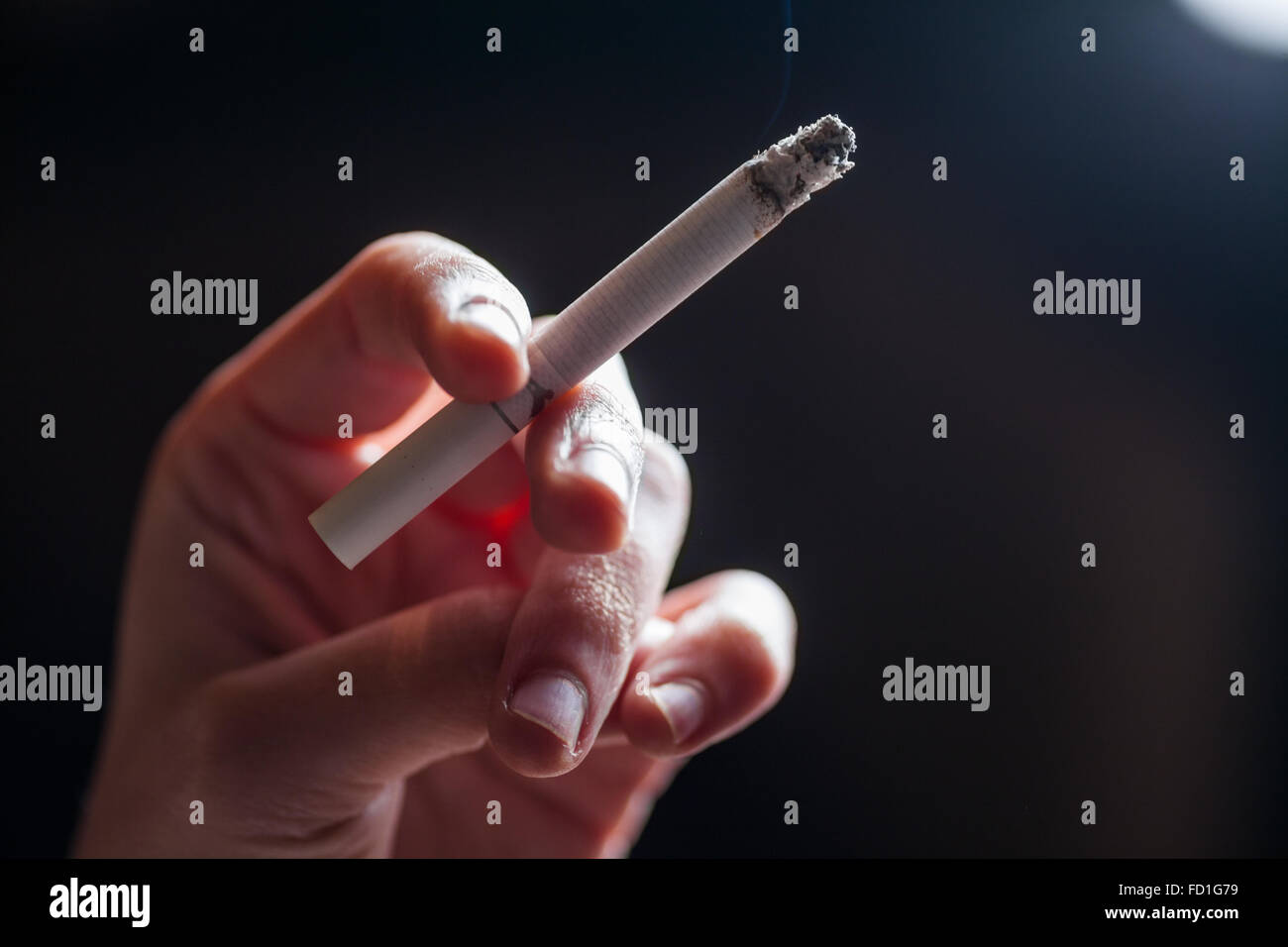 Color image of a hand holding a cigarette Stock Photo - Alamy