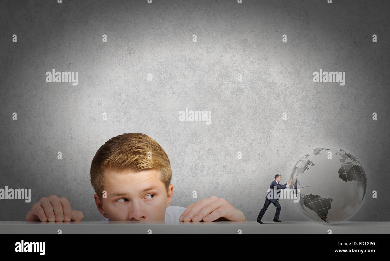 Young man looking out from under the table at businessman Stock Photo ...