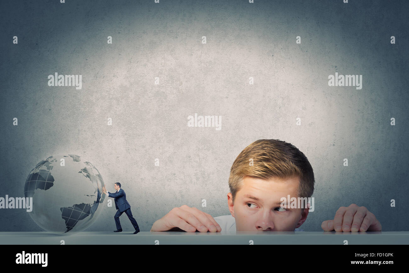 Young man looking out from under the table at businessman Stock Photo ...