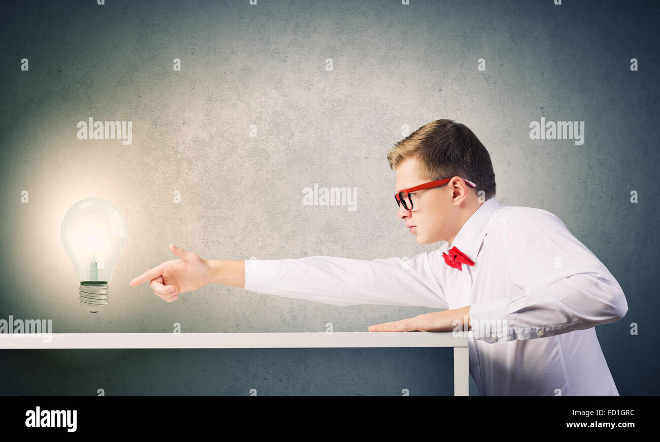 Young man pointing at electric bulb with finger Stock Photo - Alamy