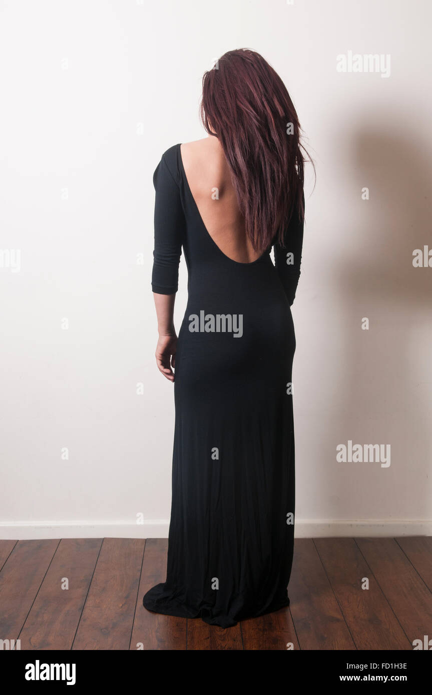 Rear view of a woman in long black dress standing indoors Stock Photo ...