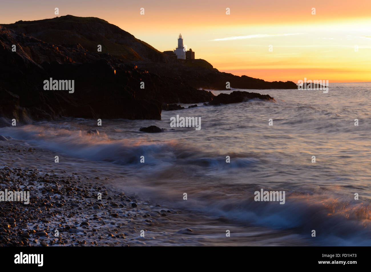waves on pebble beach at sunrise over Mumbles Lighthouse, Gower Wales ...