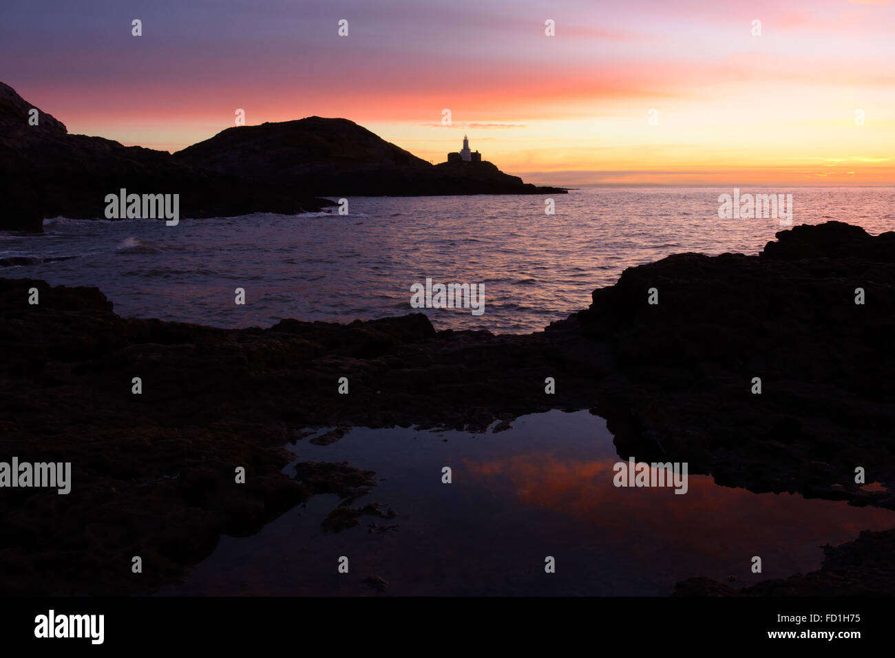 crimson sunrise reflects in rock pool at Mumbles Lighthouse, Gower ...