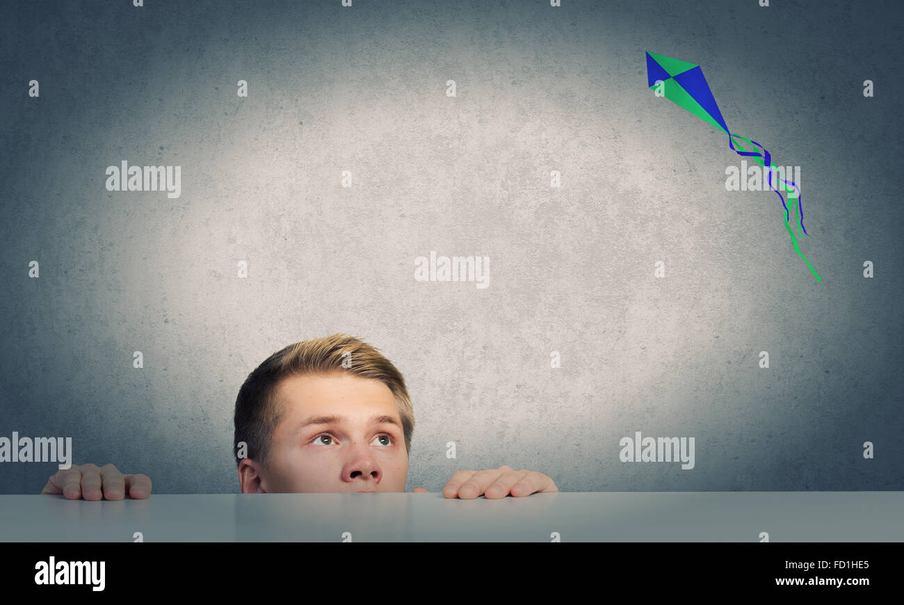 Young man looking out from under the table Stock Photo - Alamy