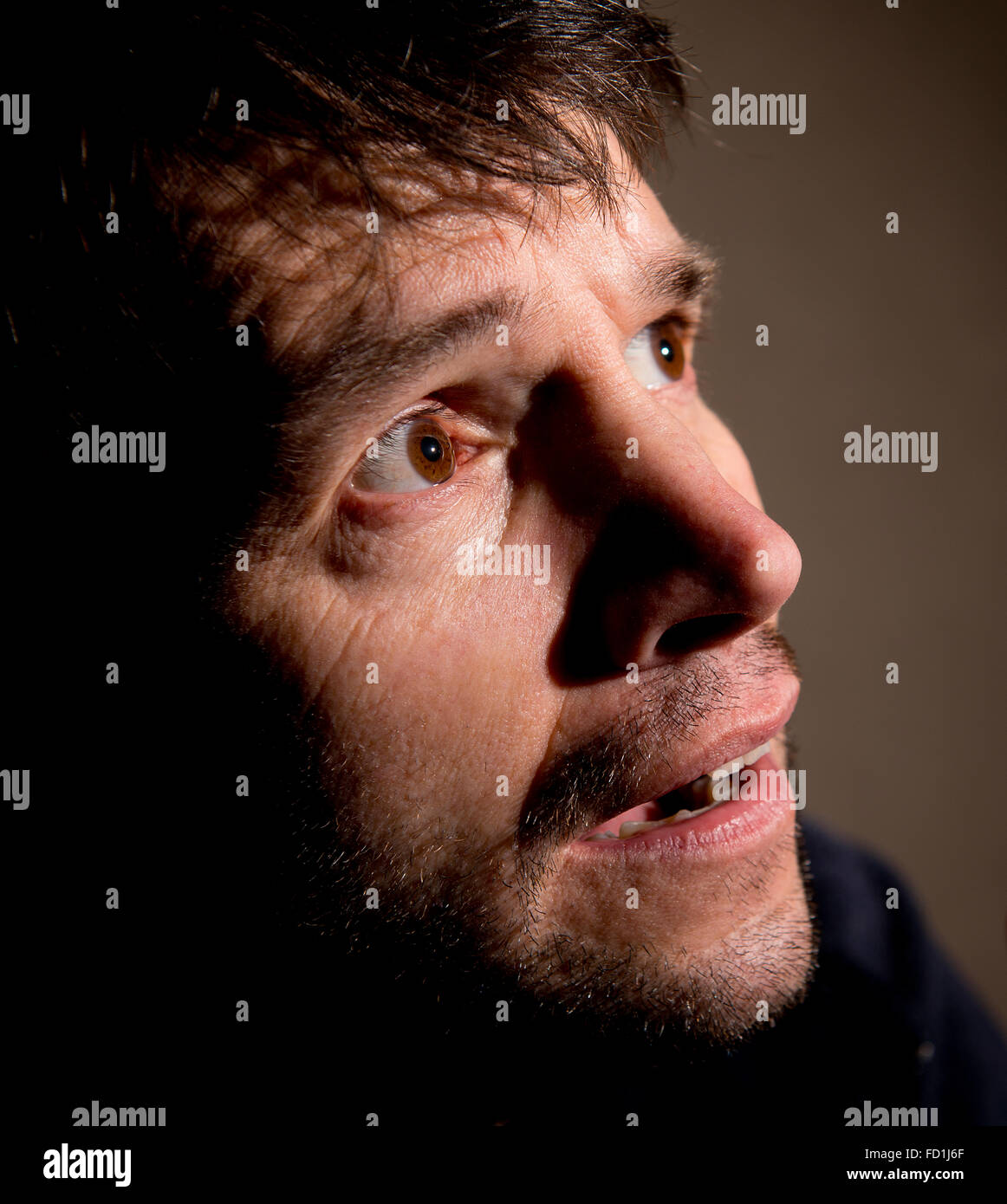 Close up, side view portrait, of a man with fear in his eyes as he ...