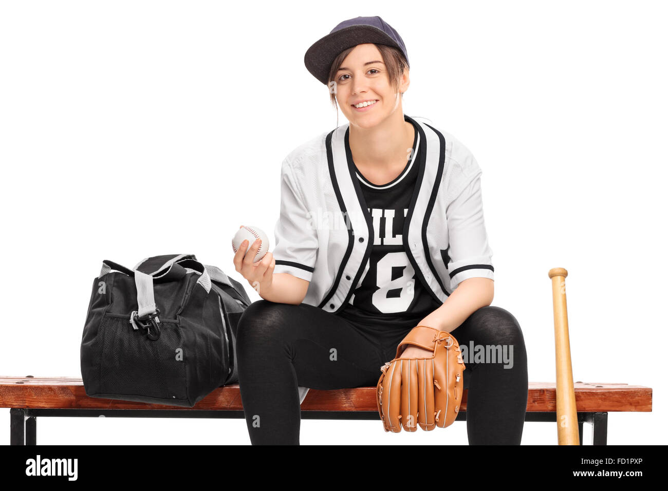 Young female baseball player seated on a wooden bench and looking at ...