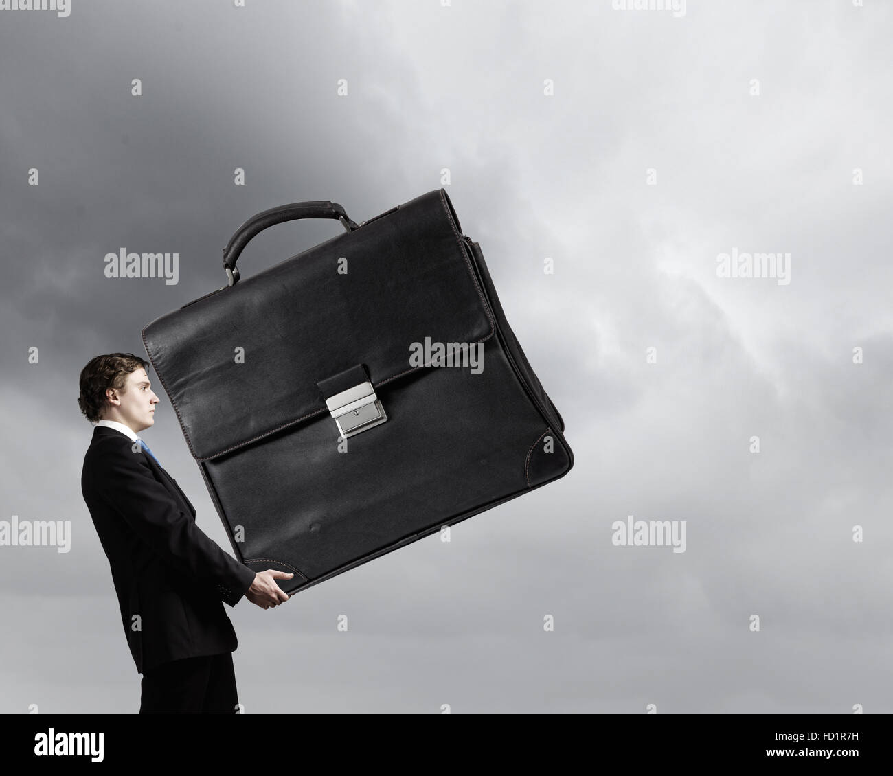 Young determined businessman carrying big heavy suitcase Stock Photo ...