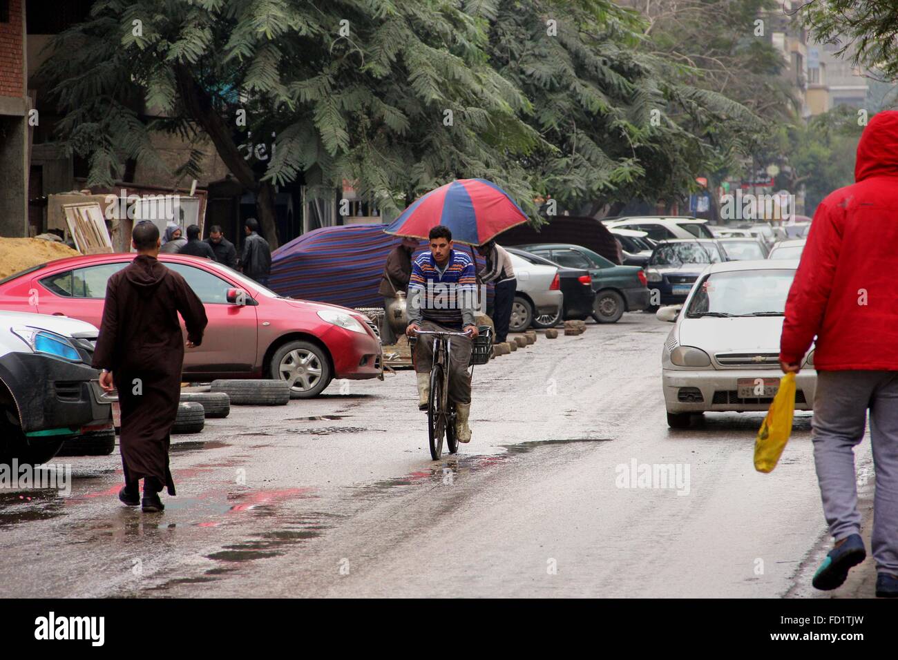 Cairo, Egypt. 28th Jan, 2016. Egyptians walk in a street flooded by ...