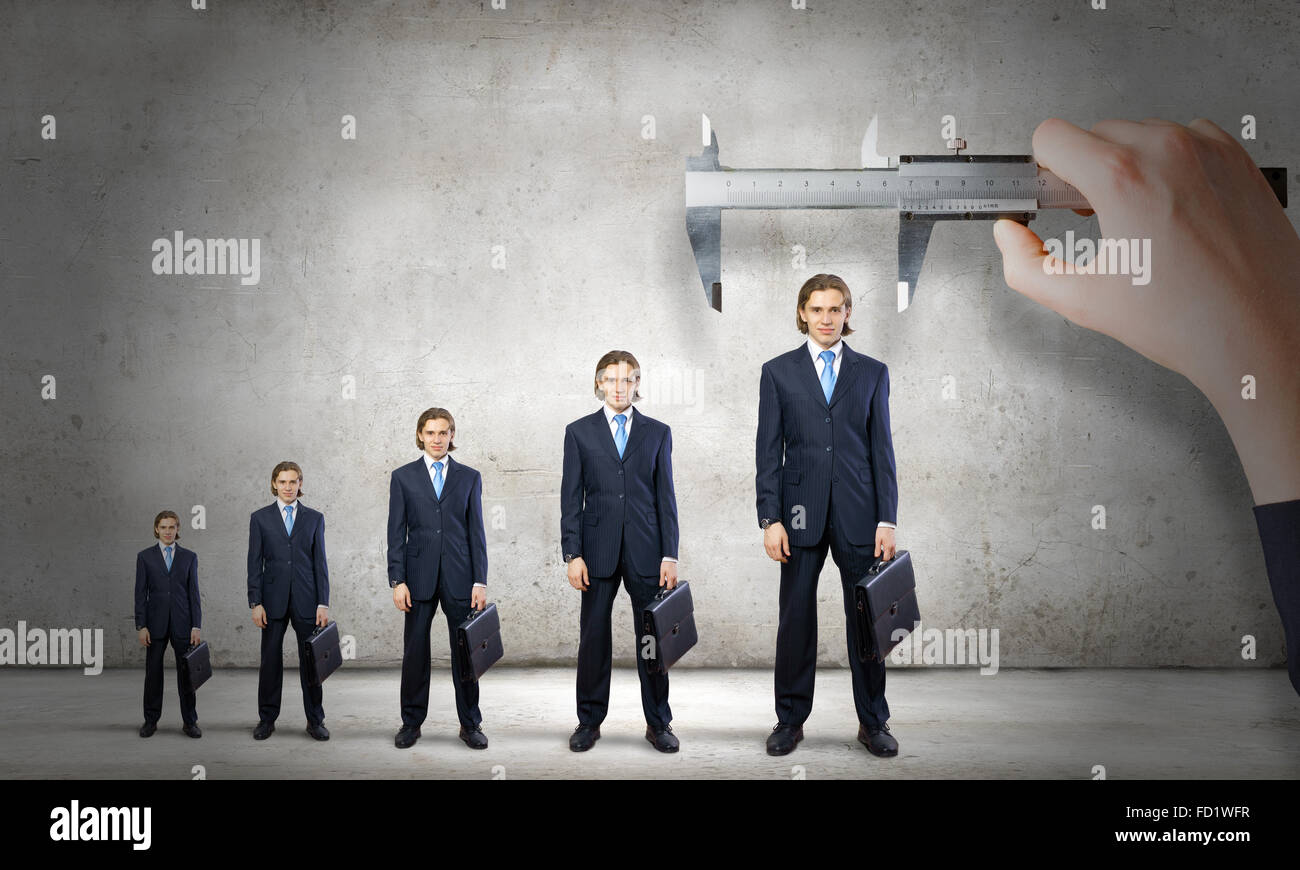 Close up male hand measuring miniatures of businesspeople Stock Photo ...