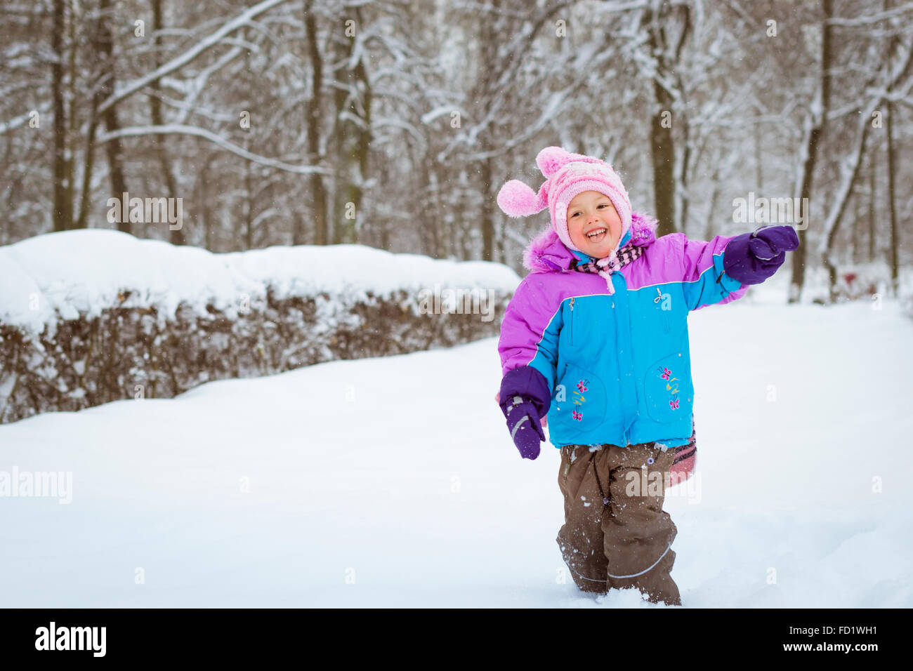 Cheerful little girl playing with snow in Park Stock Photo - Alamy