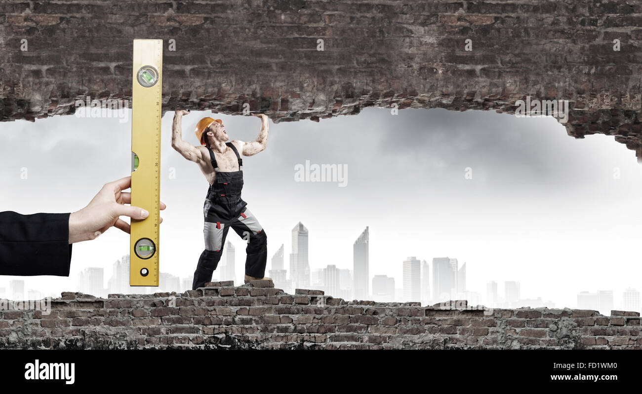 Strong man builder lifting up brick wall Stock Photo - Alamy