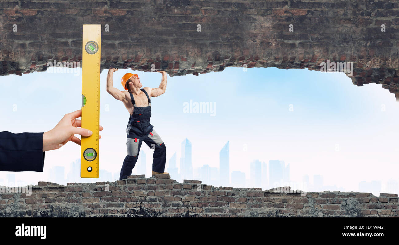 Strong man builder lifting up brick wall Stock Photo - Alamy