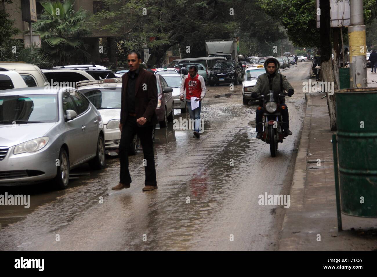 Cairo, Egypt. 27th Jan, 2016. Egyptians walk in a street flooded by ...