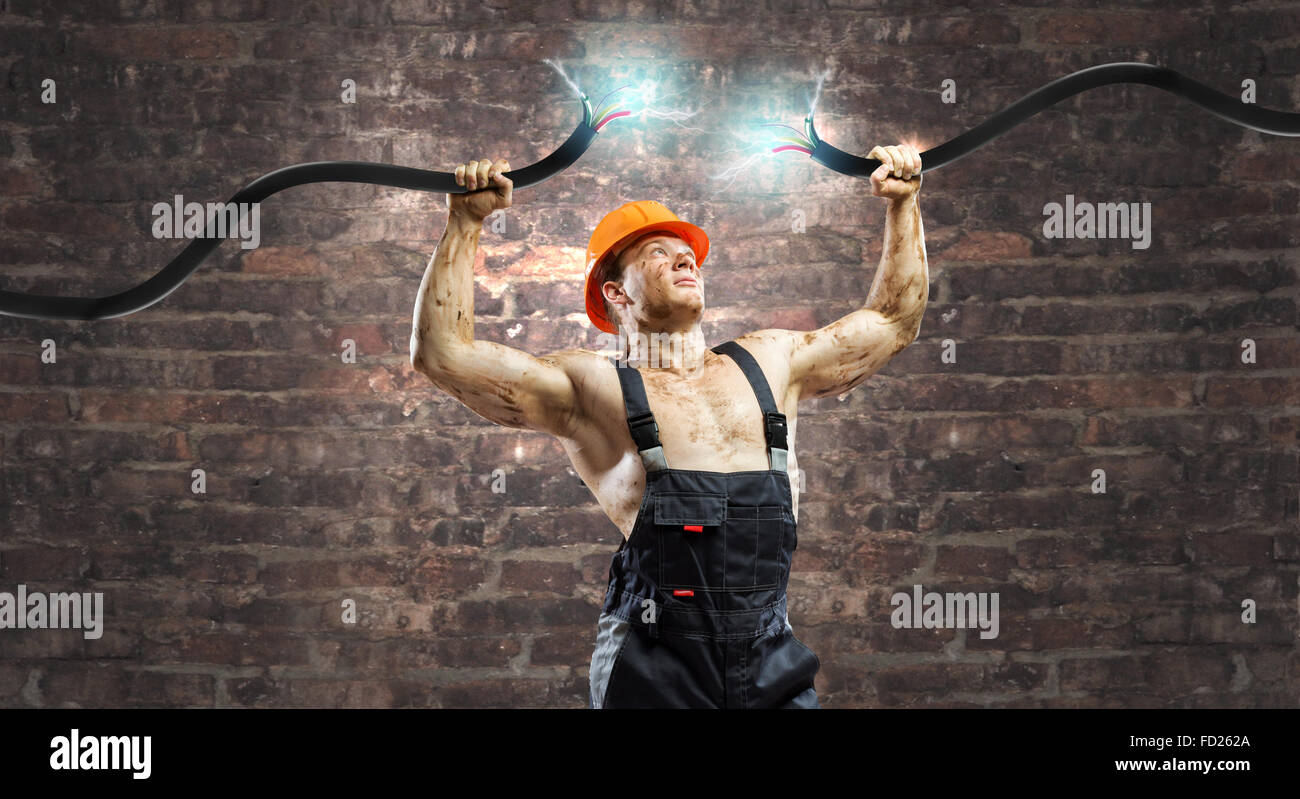 Strong man in uniform tearing electricity cable with hands Stock Photo ...