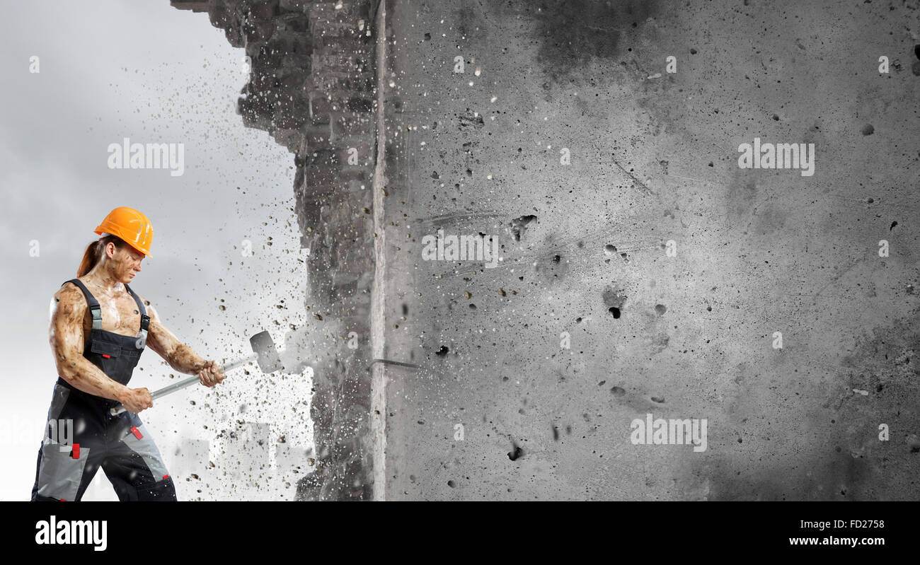 Strong man in uniform breaking wall with hammer Stock Photo - Alamy