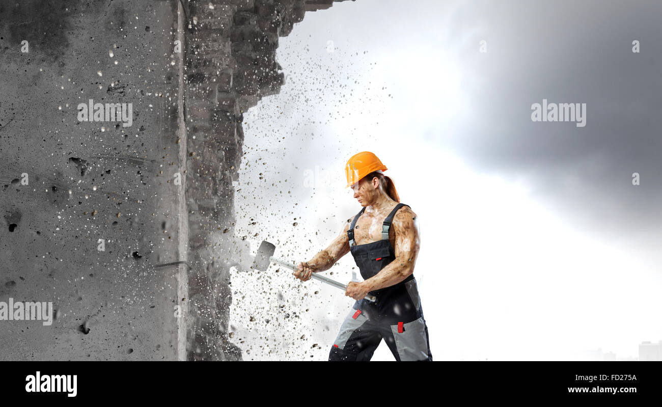 Strong man in uniform breaking wall with hammer Stock Photo - Alamy
