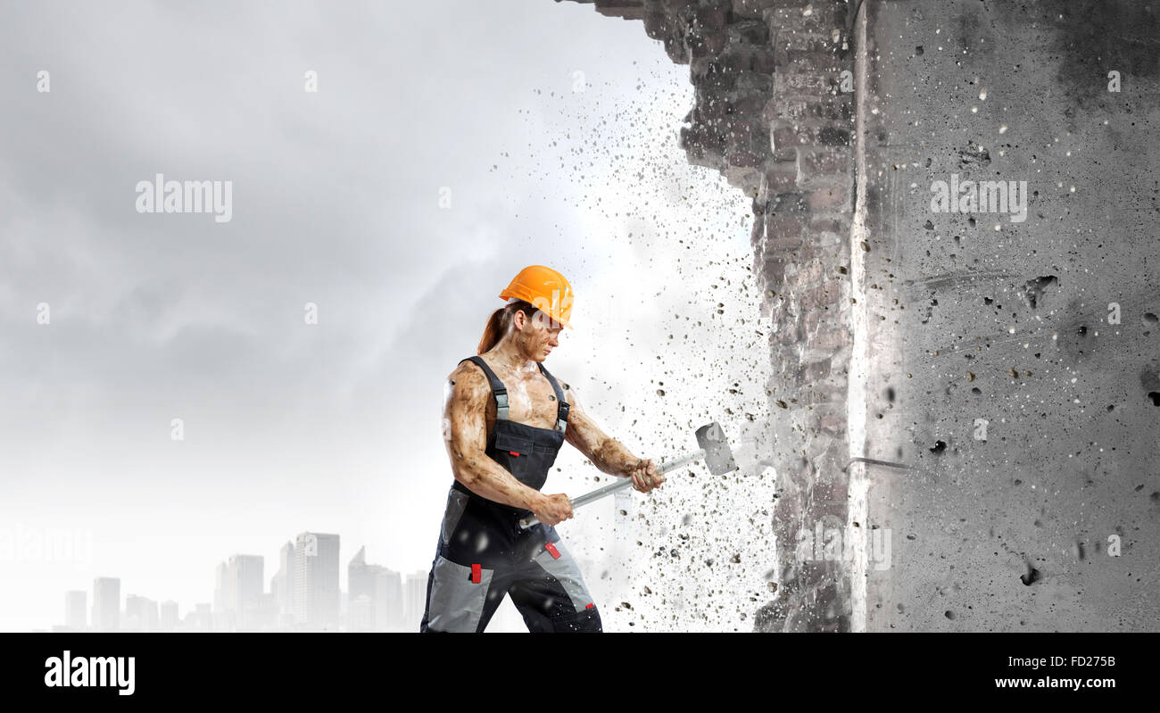 Strong man in uniform breaking brick wall with hammer Stock Photo - Alamy
