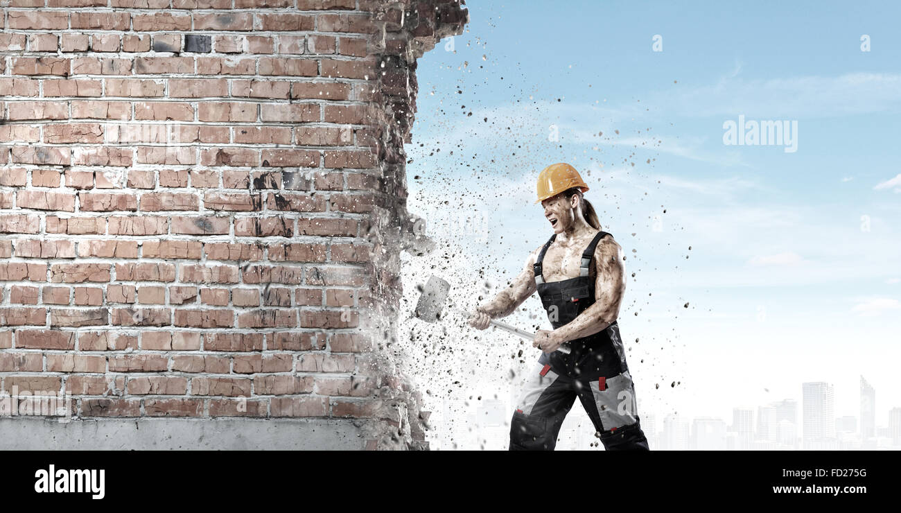 Strong man in uniform breaking brick wall with hammer Stock Photo - Alamy
