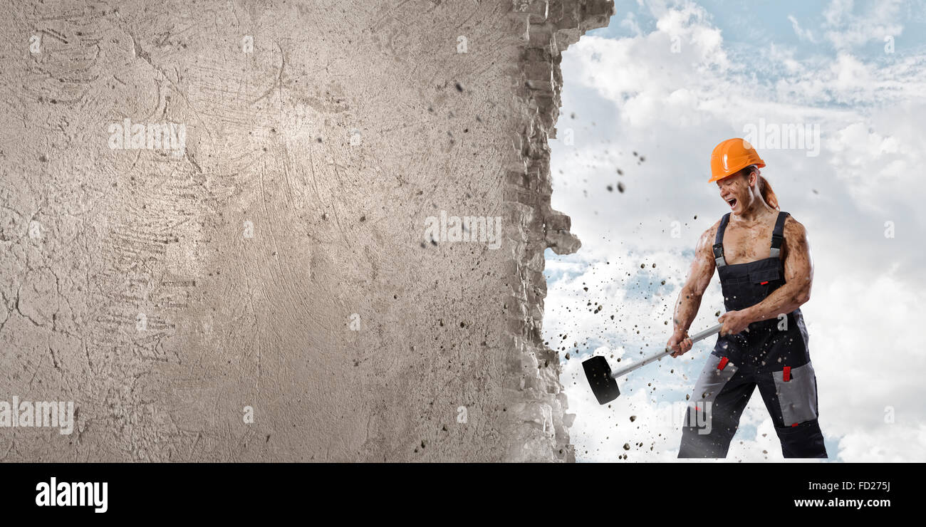 Strong man in uniform breaking wall with hammer Stock Photo - Alamy