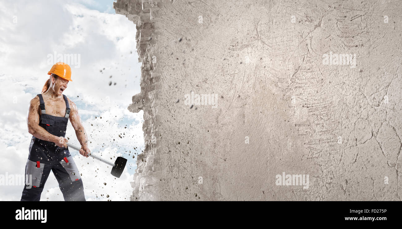 Strong man in uniform breaking wall with hammer Stock Photo - Alamy