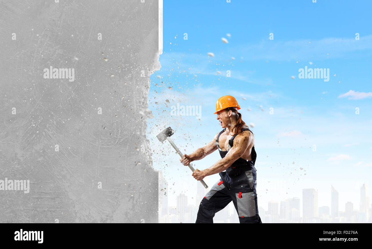 Strong man in uniform breaking wall with hammer Stock Photo - Alamy