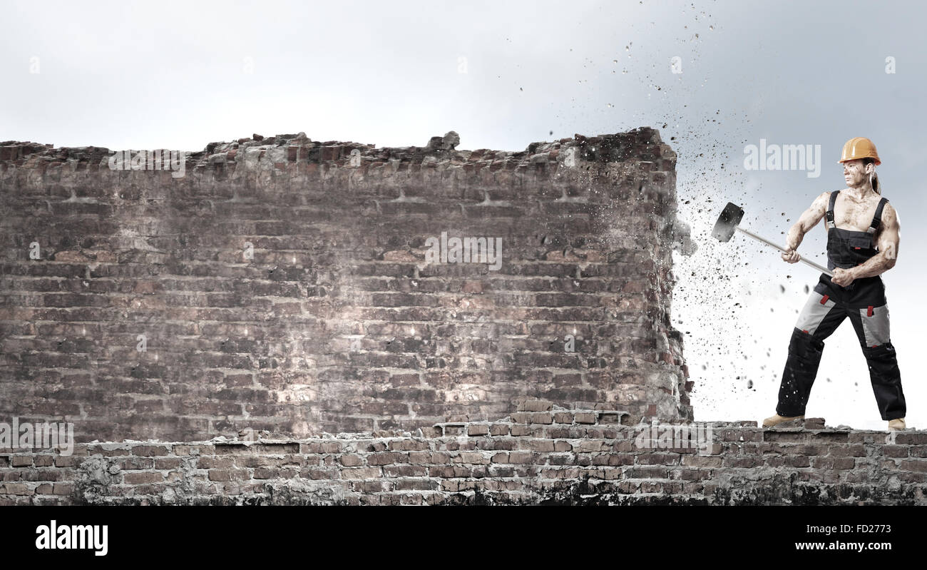 Strong man in uniform breaking brick wall with hammer Stock Photo - Alamy