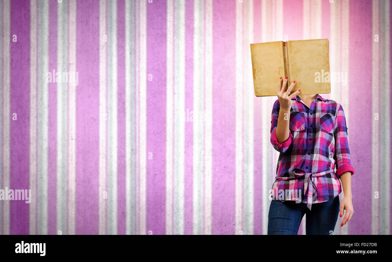 Young woman in casual hiding face behind reading Stock Photo - Alamy
