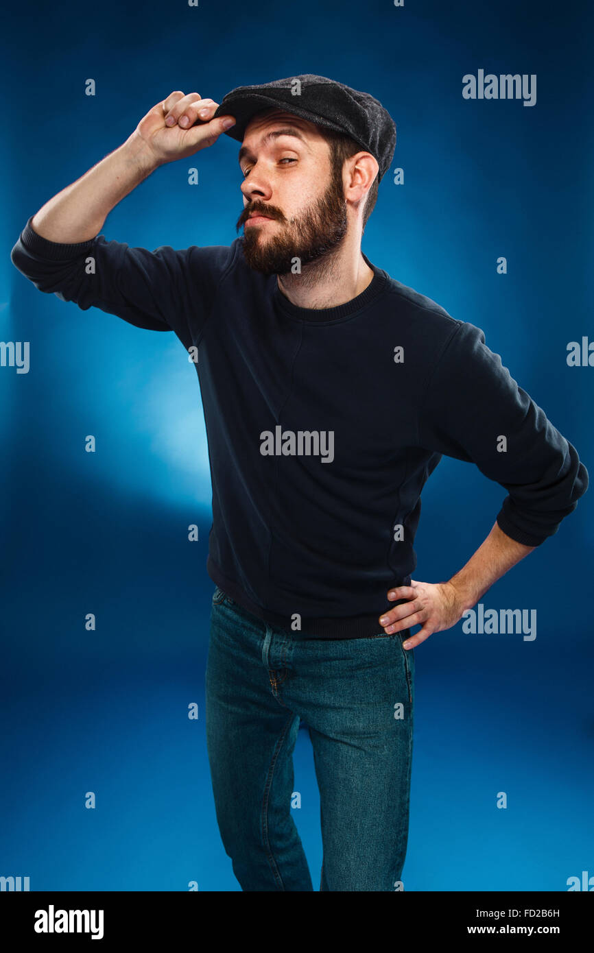 The inquisitive young man in cap on blue background Stock Photo - Alamy