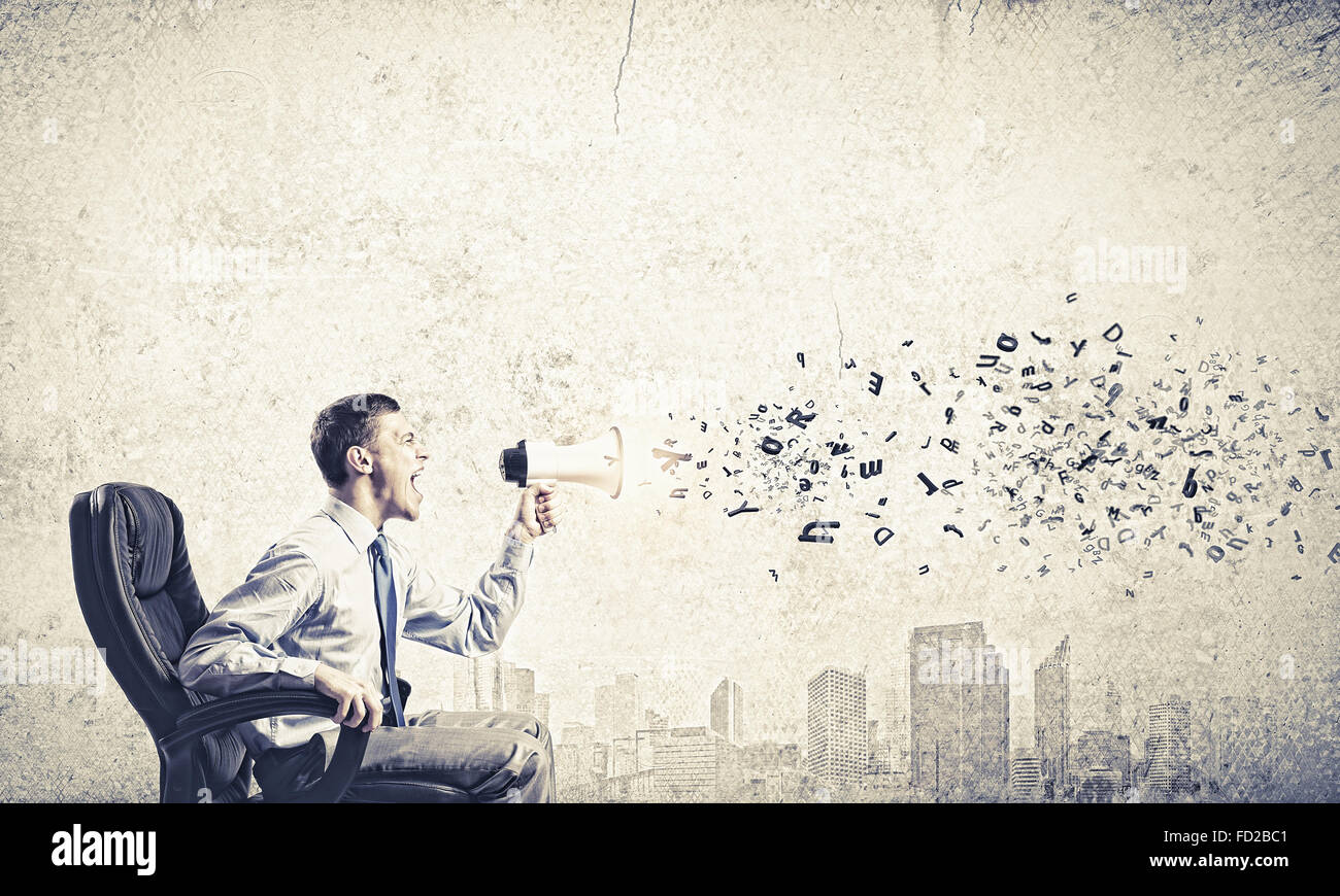 Young angry businessman sitting on chair and screaming in megaphone ...