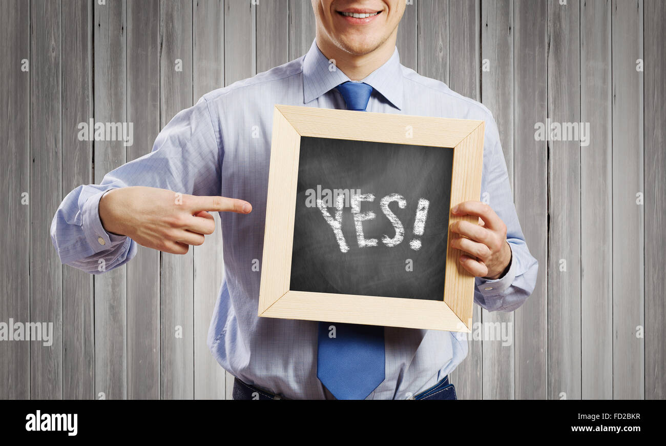 Young smiling businessman holding chalkboard with yes word Stock Photo ...