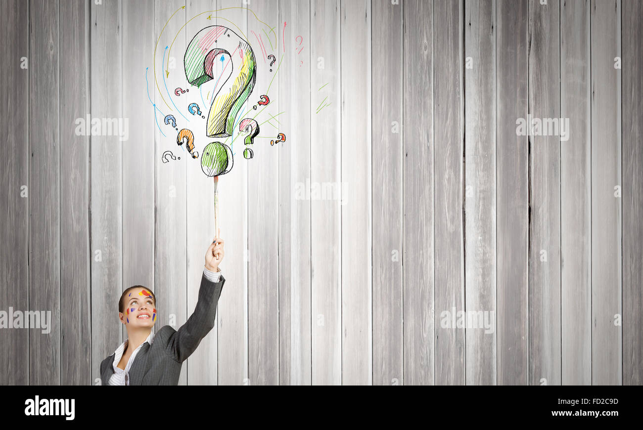 Young attractive businesswoman painting question mark with paint brush ...