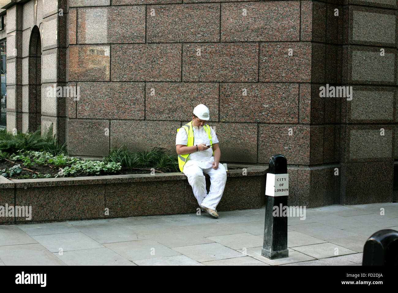 Workman using his mobile phone on a street near Mansion House, London ...