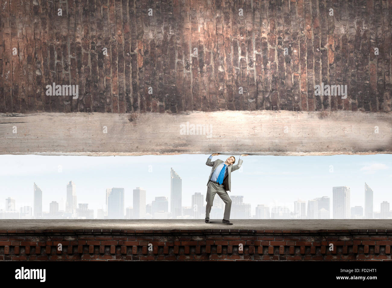 Young powerful businessman lifting brick wall above head Stock Photo ...