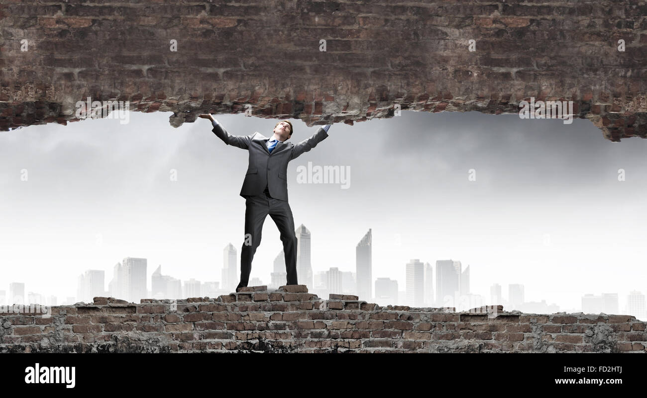 Young powerful businessman lifting brick wall above head Stock Photo ...