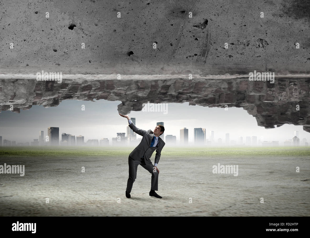 Young powerful businessman lifting brick wall above head Stock Photo ...