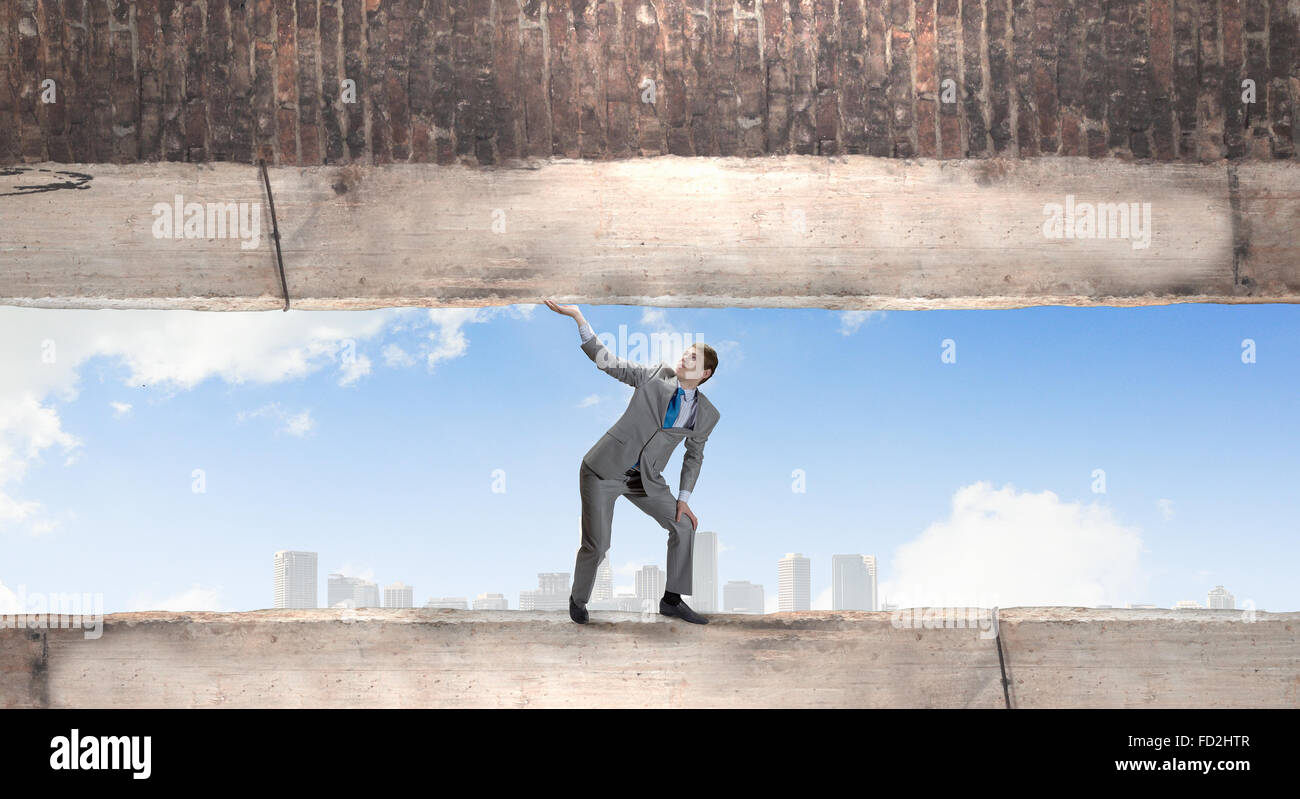 Young powerful businessman lifting brick wall above head Stock Photo ...