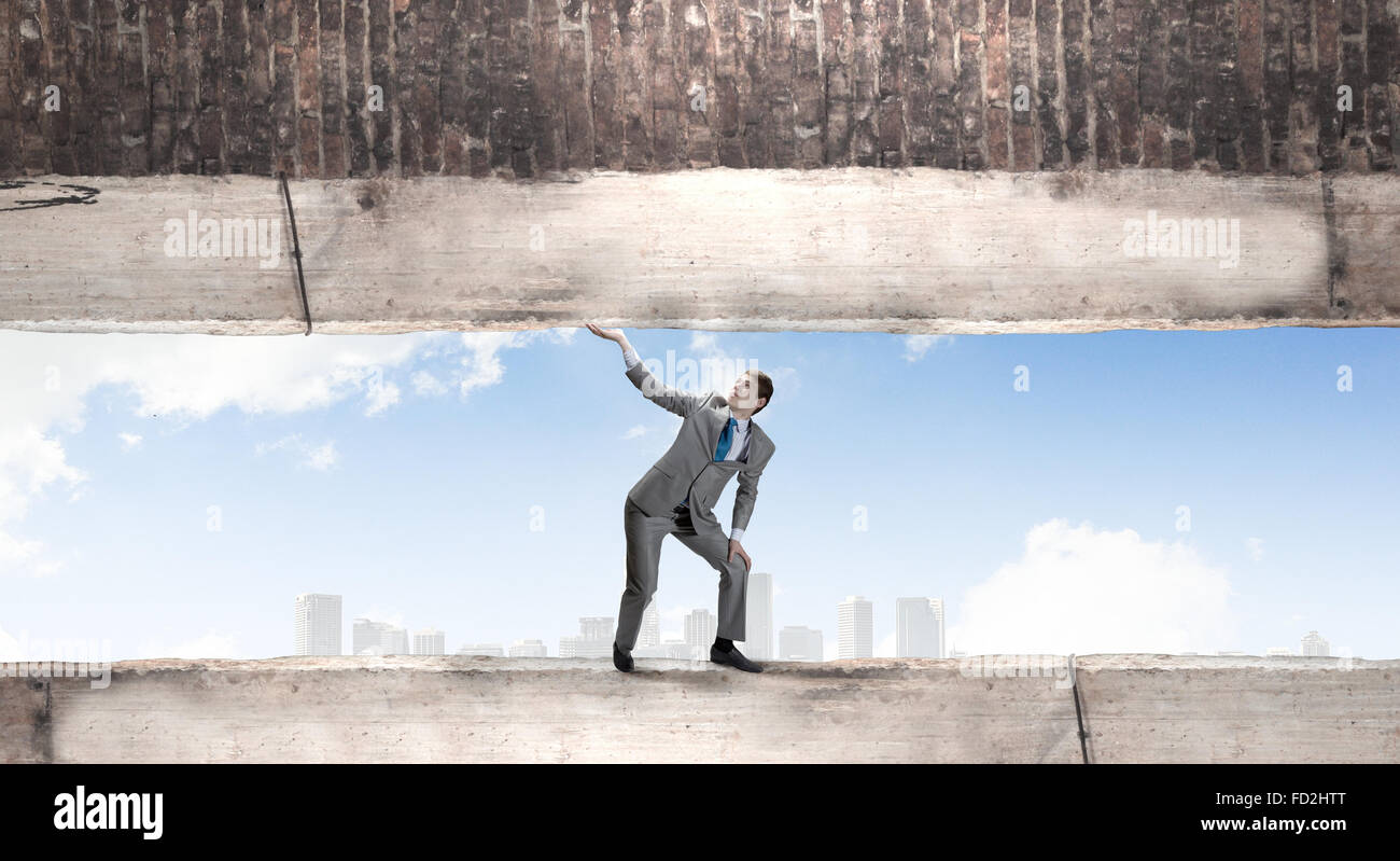 Young powerful businessman lifting brick wall above head Stock Photo ...