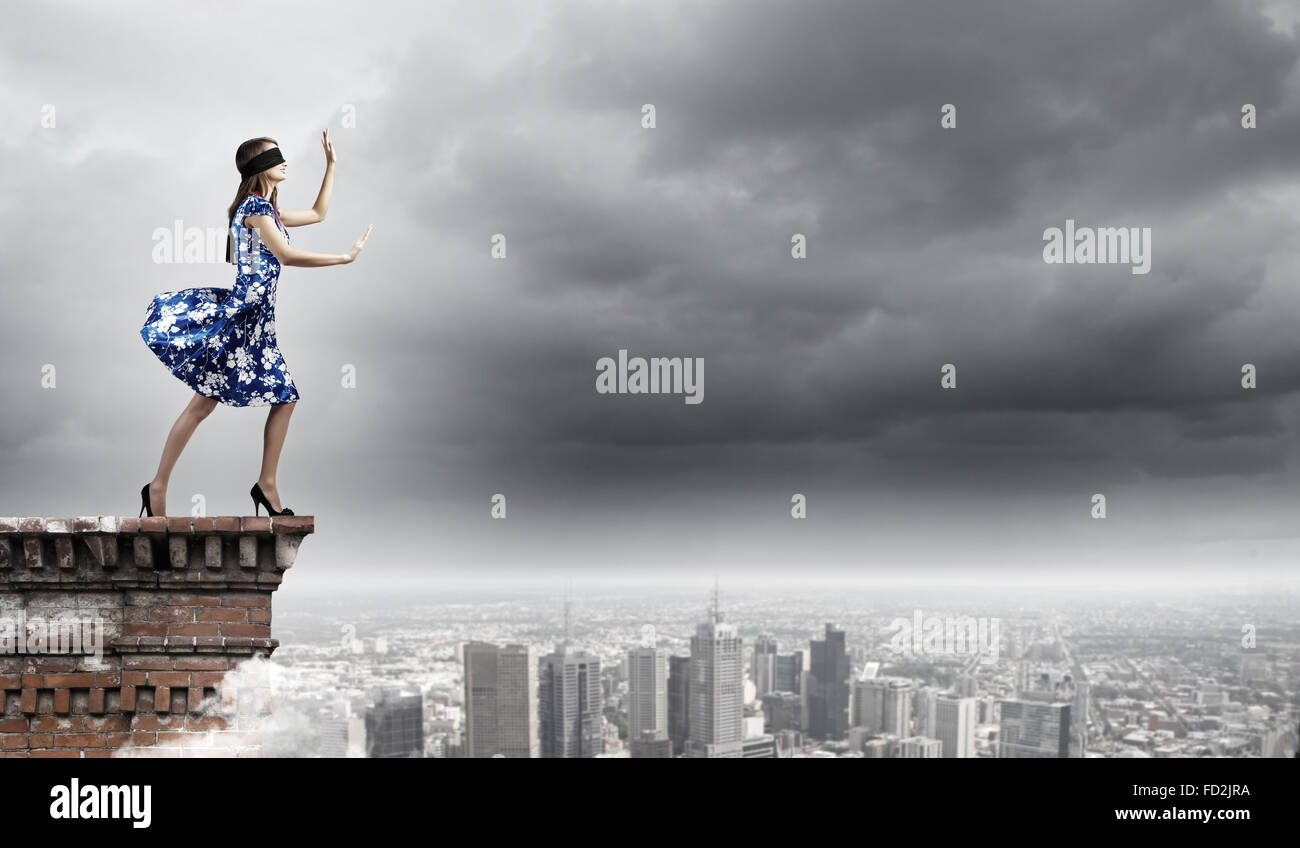 Young woman in blue dress standing on roof edge Stock Photo - Alamy