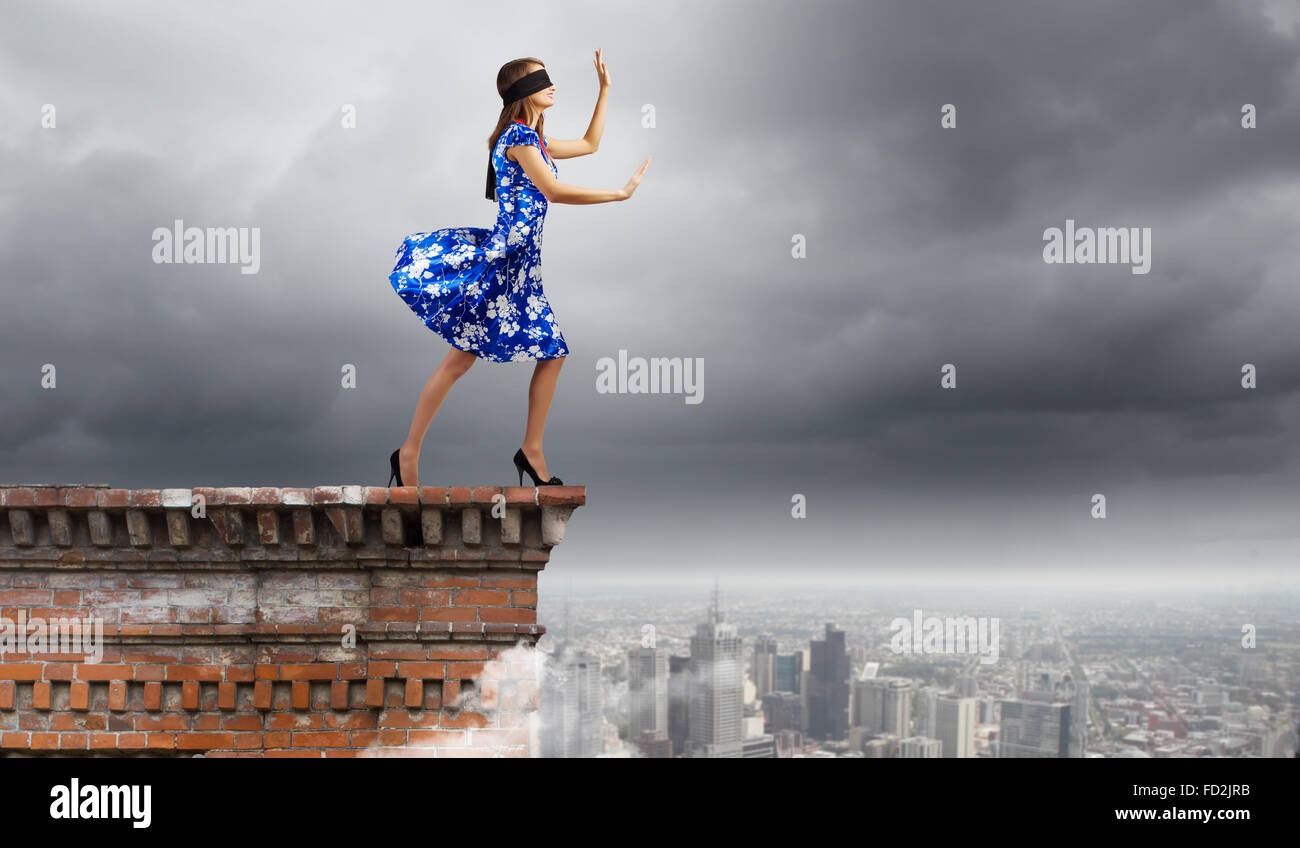 Young woman in blue dress standing on roof edge Stock Photo - Alamy