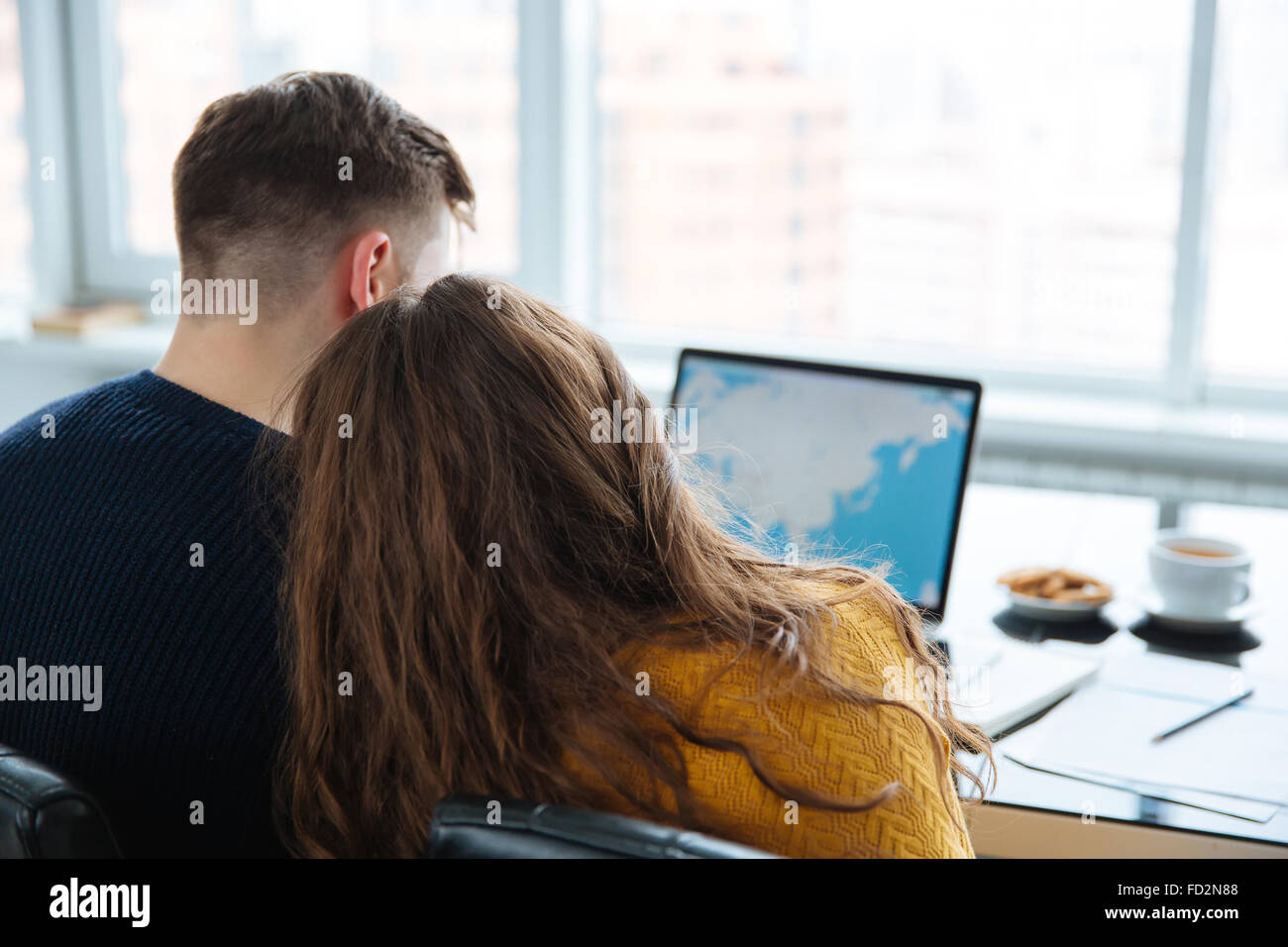 Back view portrait of a couple using laptop computer at home Stock ...