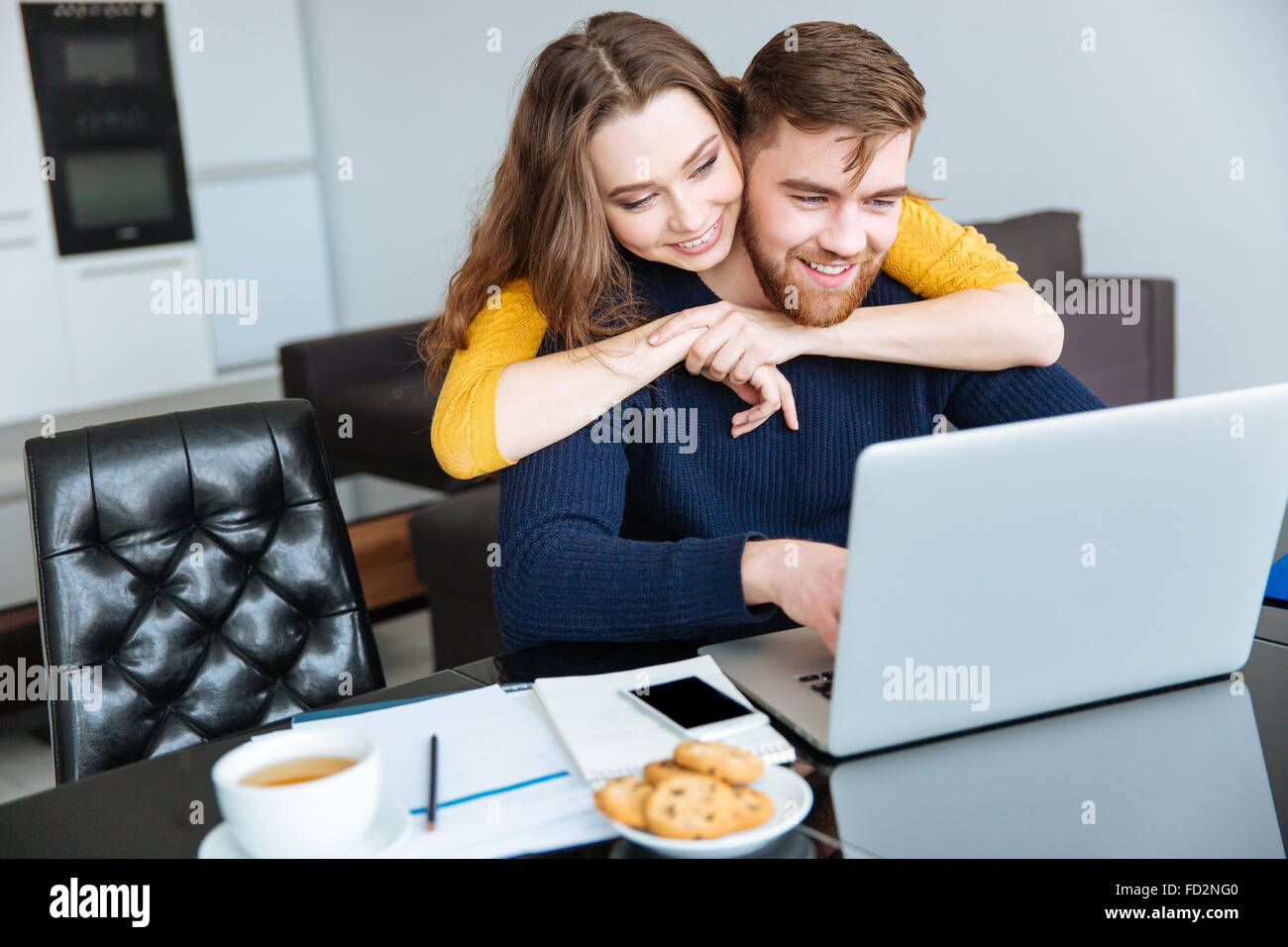 Portrait of a smiling beautiful couple using laptop computer at home ...