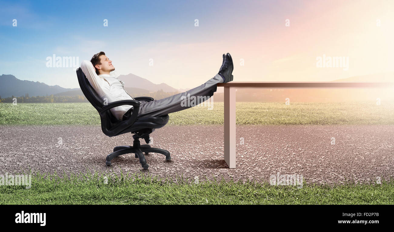 Young businessman sitting in chair with legs on table Stock Photo - Alamy