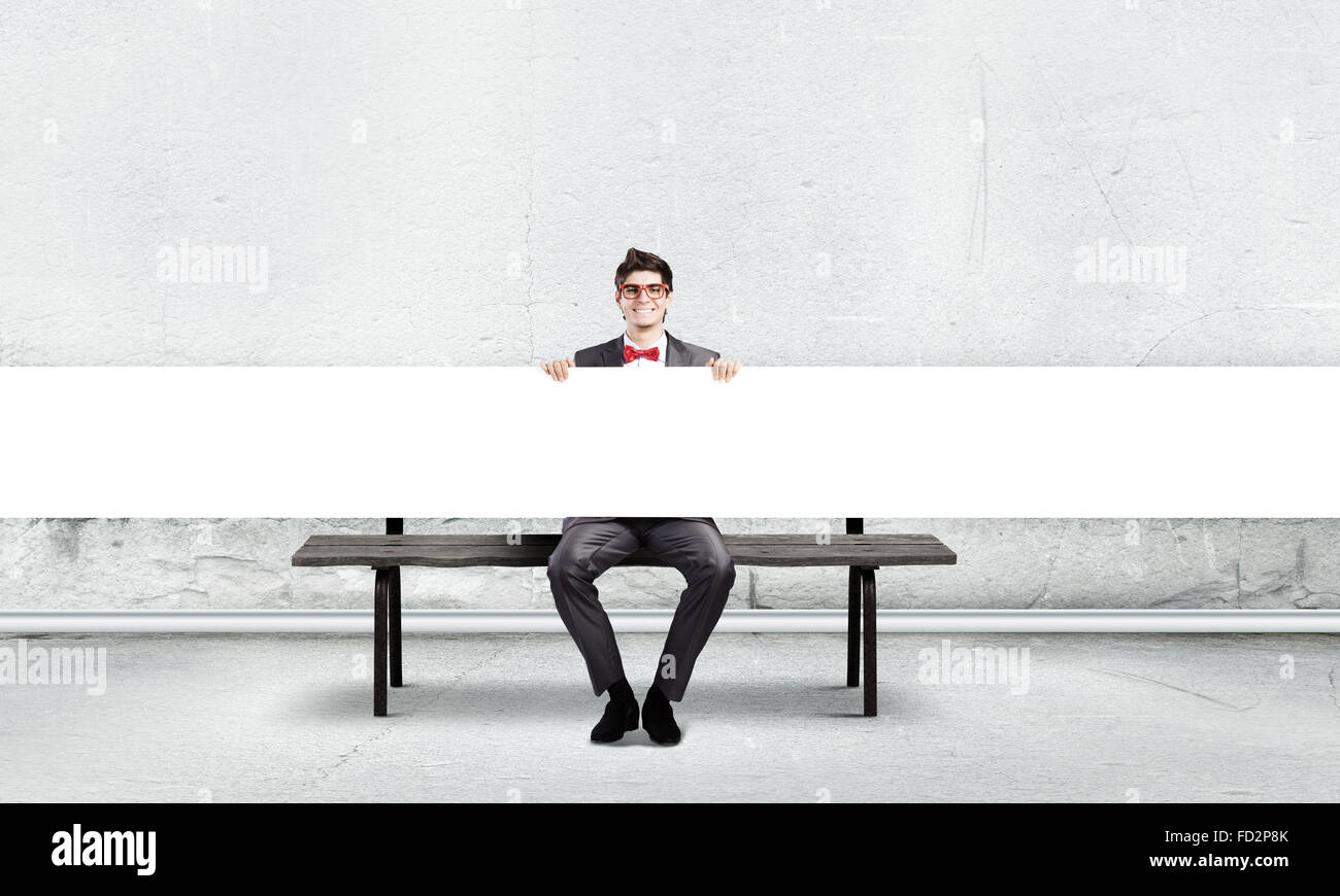 Young man in glasses sitting on bench with white banner Stock Photo - Alamy