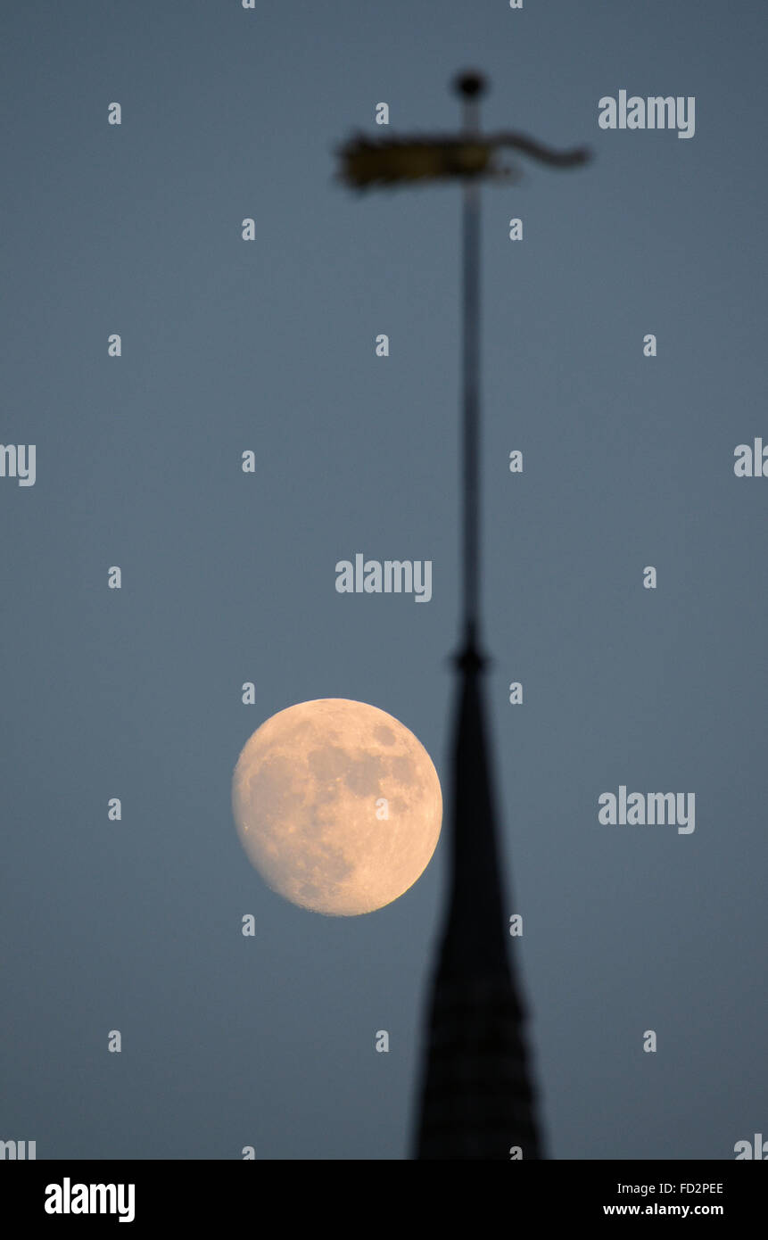 A bright, almost full moon rising behind the spire of St. Laurence ...