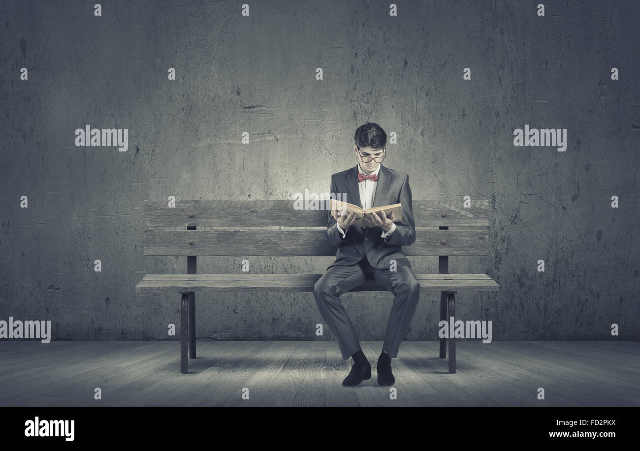 Young man in suit sitting on bench with book in hands Stock Photo - Alamy