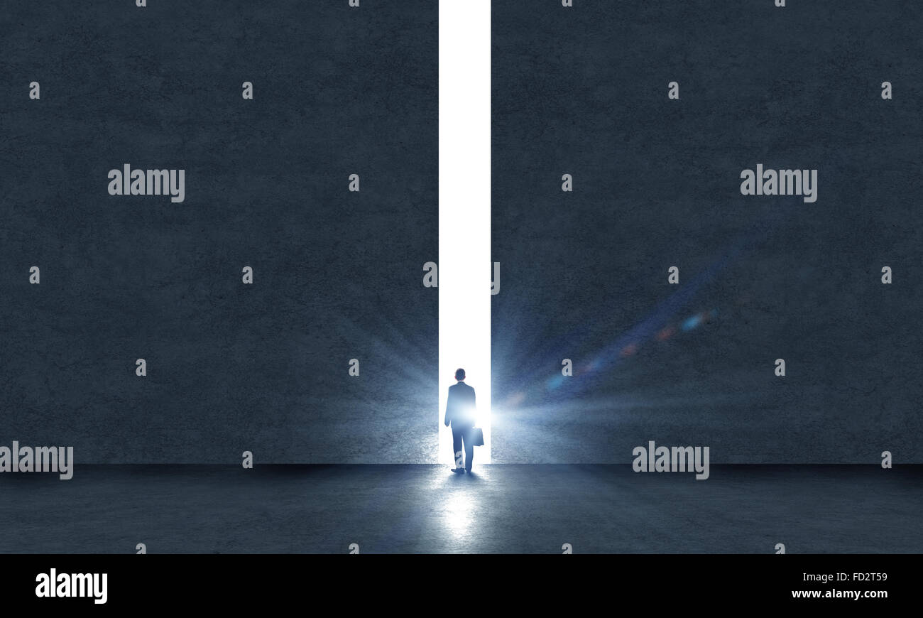 Rear view of businessman standing in light of way in wall Stock Photo ...