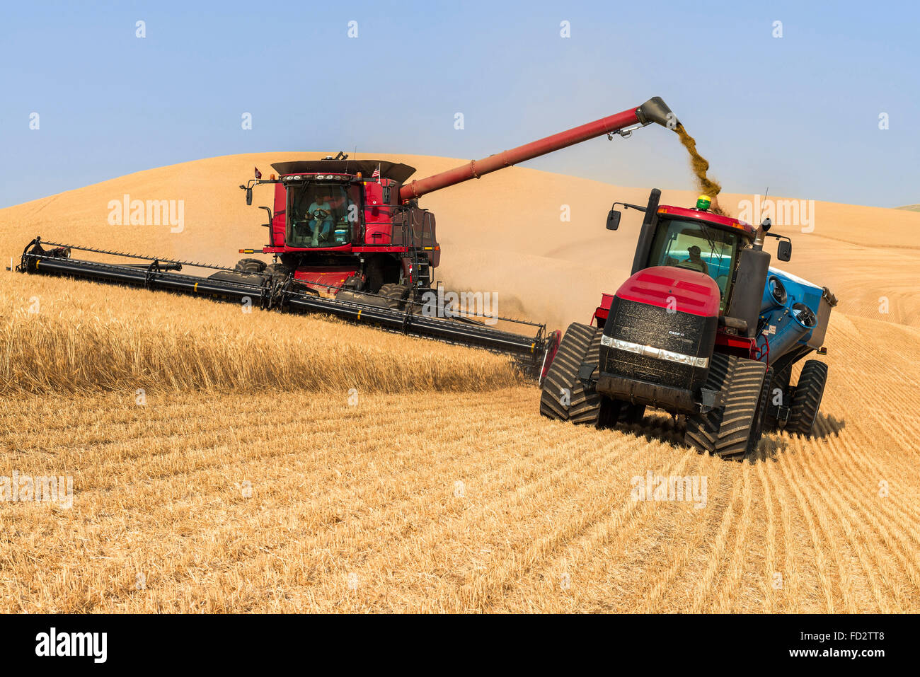One or more combines offloading grain to a tractor pulled grain cart in ...
