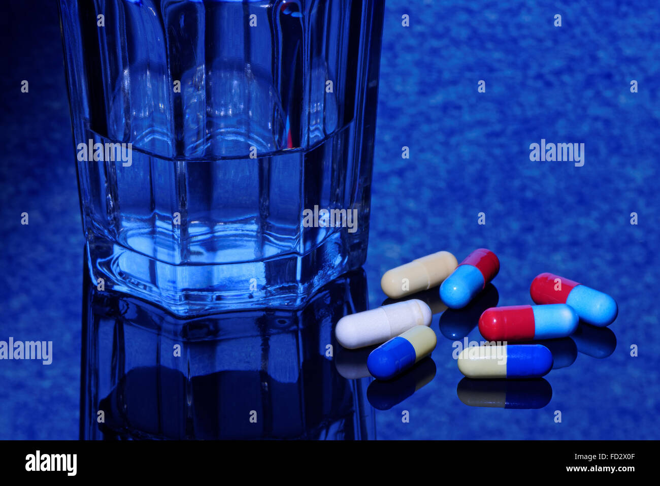 Capsules with a glass of water. Medical concept Stock Photo - Alamy