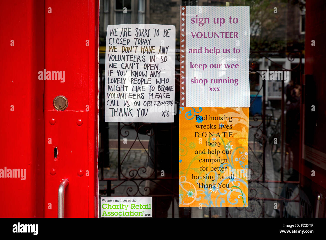 Signs in the door of a Shelter charity shop asking for volunteers and ...